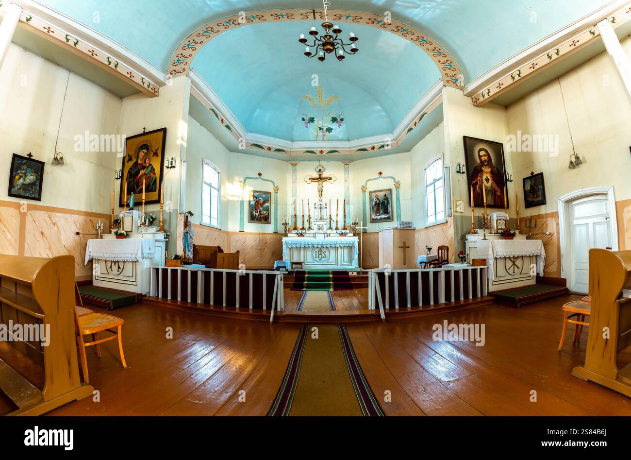 Traditional church interior featuring a light blue vaulted ceiling, central altar with crucifix ...