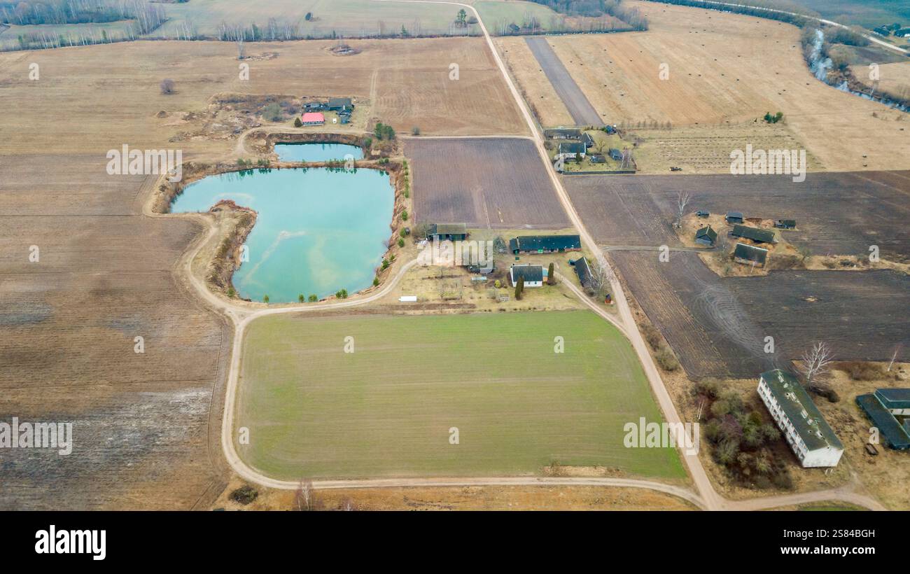 Aerial perspective of a rural area featuring a small pond, open fields ...