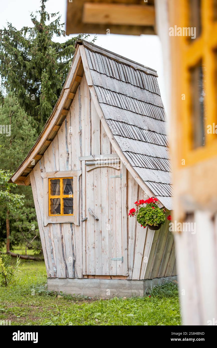 A small wooden cabin with a sloped roof, yellow framed window, and red ...