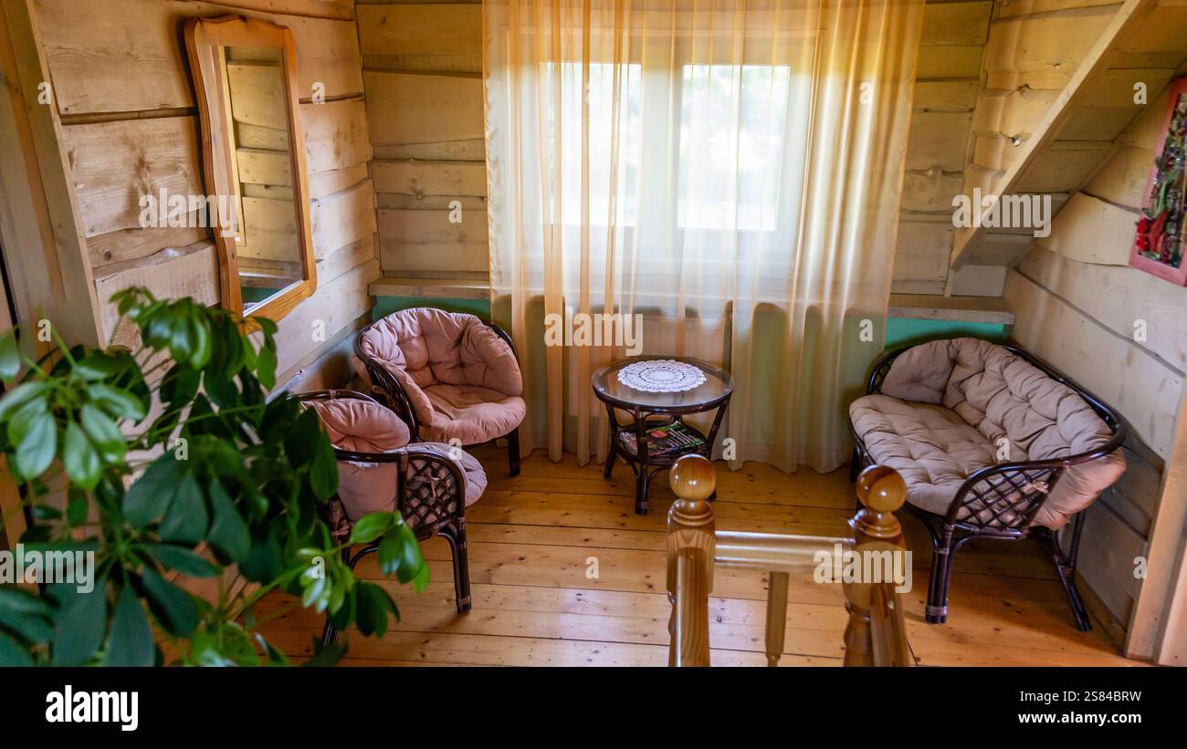 Cozy upper level room with wooden walls, wicker chairs, a round table ...