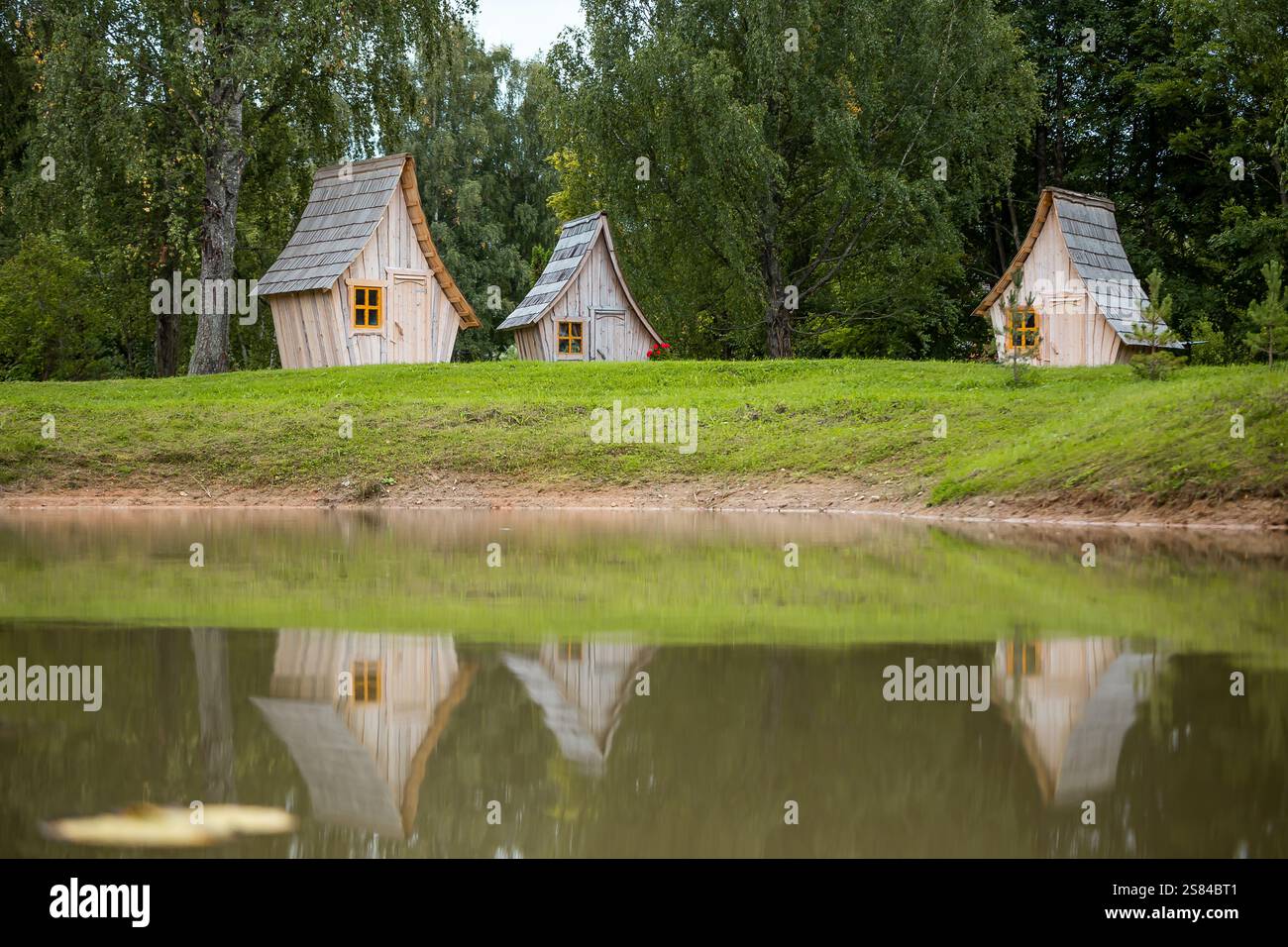 Three wooden cottages with steep roofs and yellow framed windows sit on ...