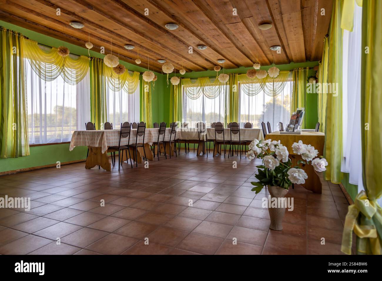 Dining space with long tables, green walls, yellow drapes, wooden ...
