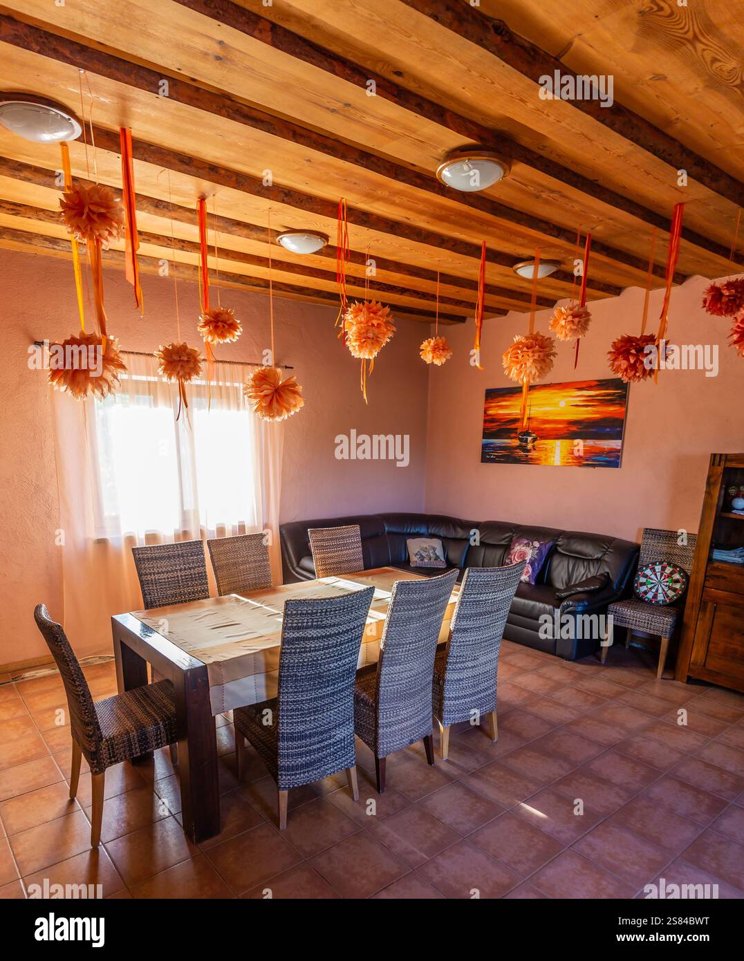 Cozy interior featuring a wooden ceiling with exposed beams, orange pom ...