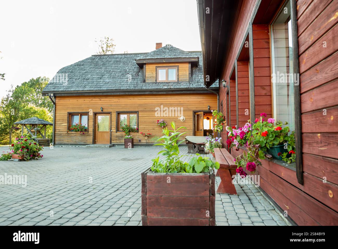 A wooden house with a steep roof and dormer window, surrounded by a ...