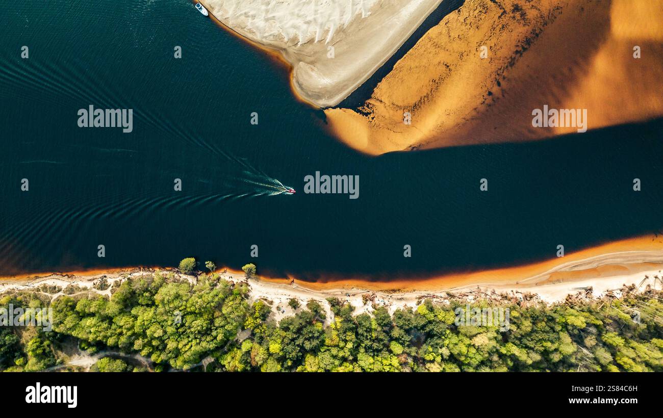 Aerial perspective of a dark blue river bordered by golden brown ...
