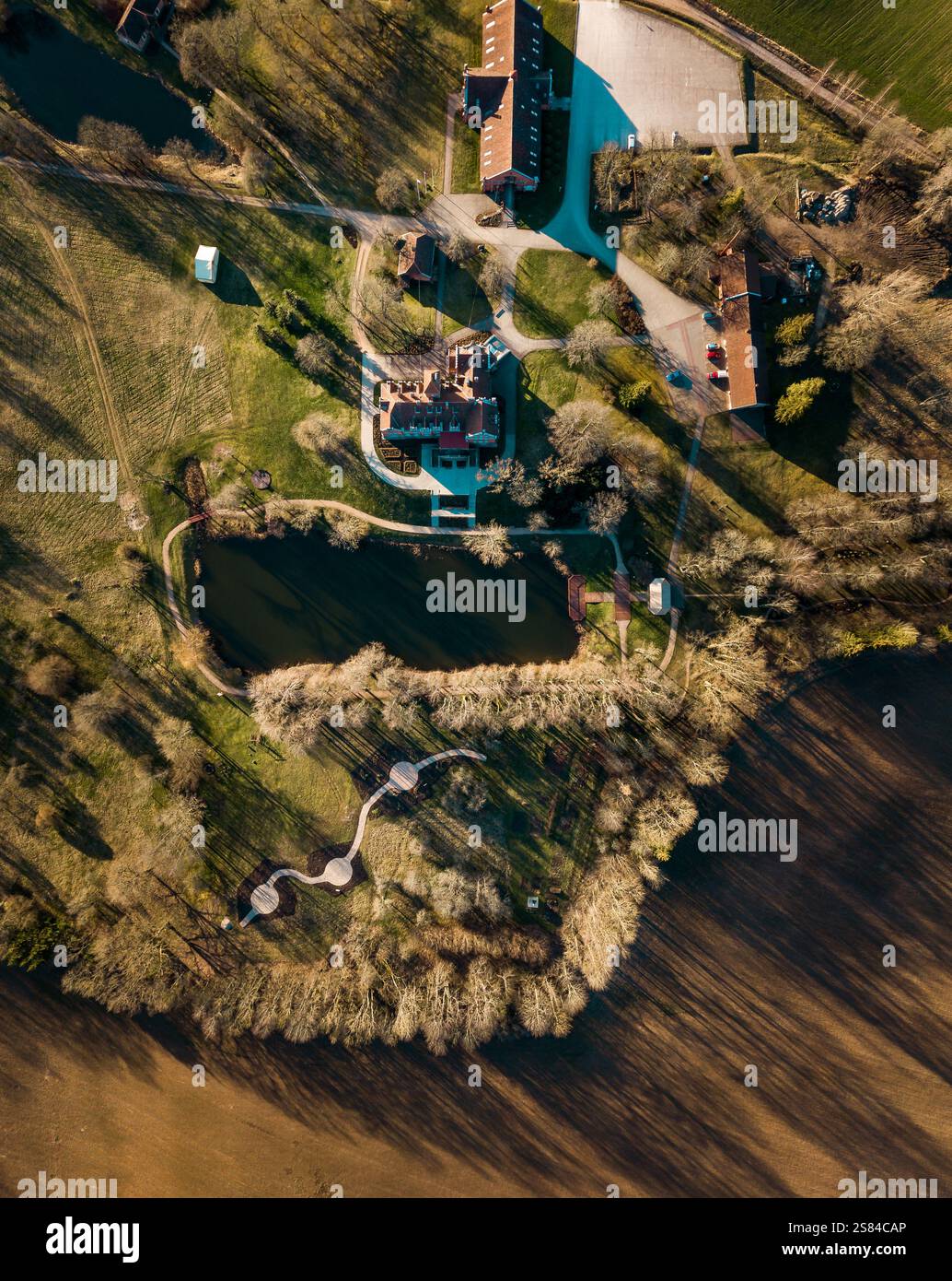 A countryside estate with a red roofed building, open fields, trees, a ...
