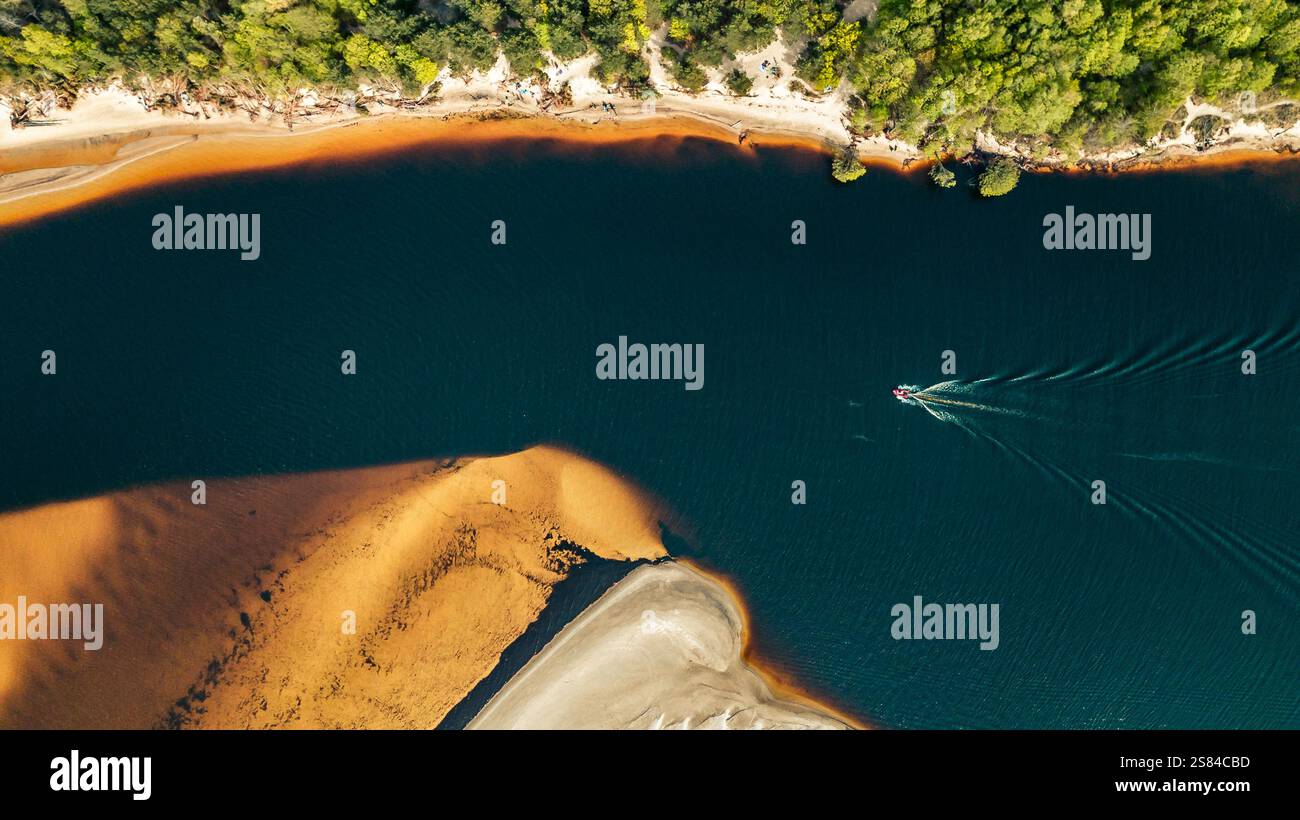 Aerial perspective of a dark blue river bordered by orange brown ...