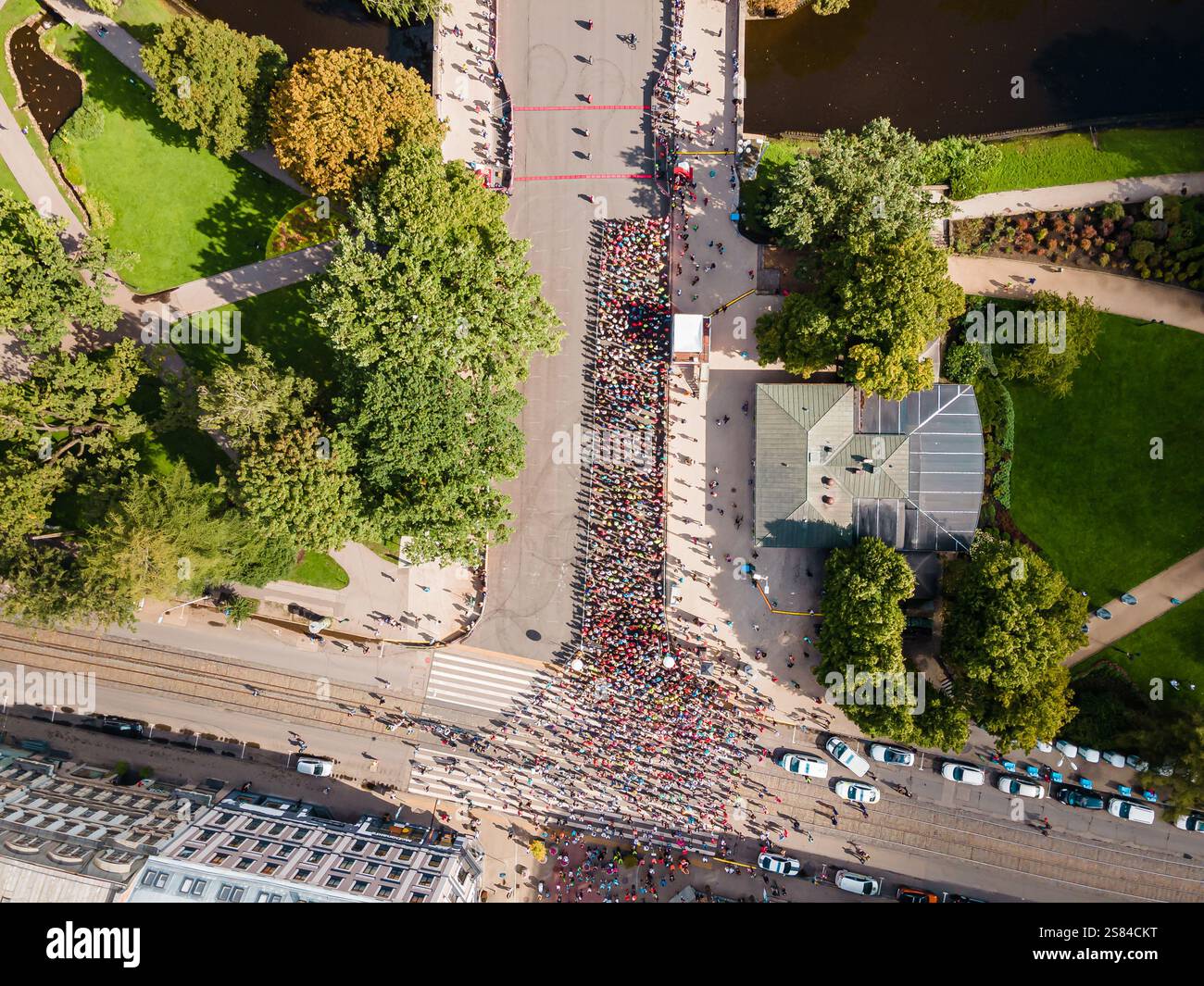Large crowd gathers on a road with a red line, surrounded by lawns ...
