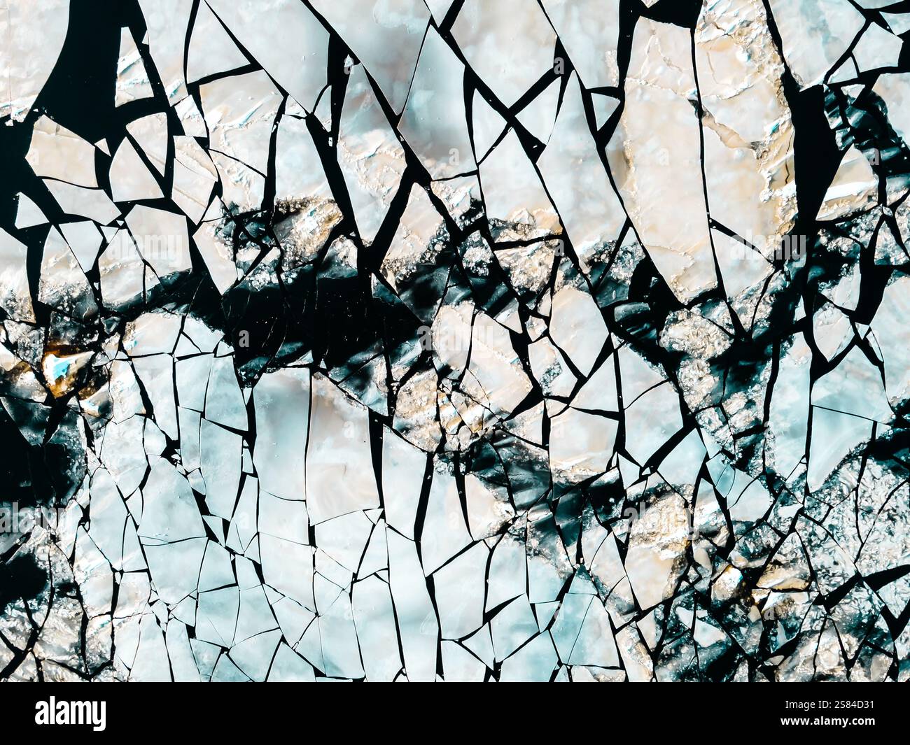 A detailed view of shattered glass featuring jagged fragments, light ...