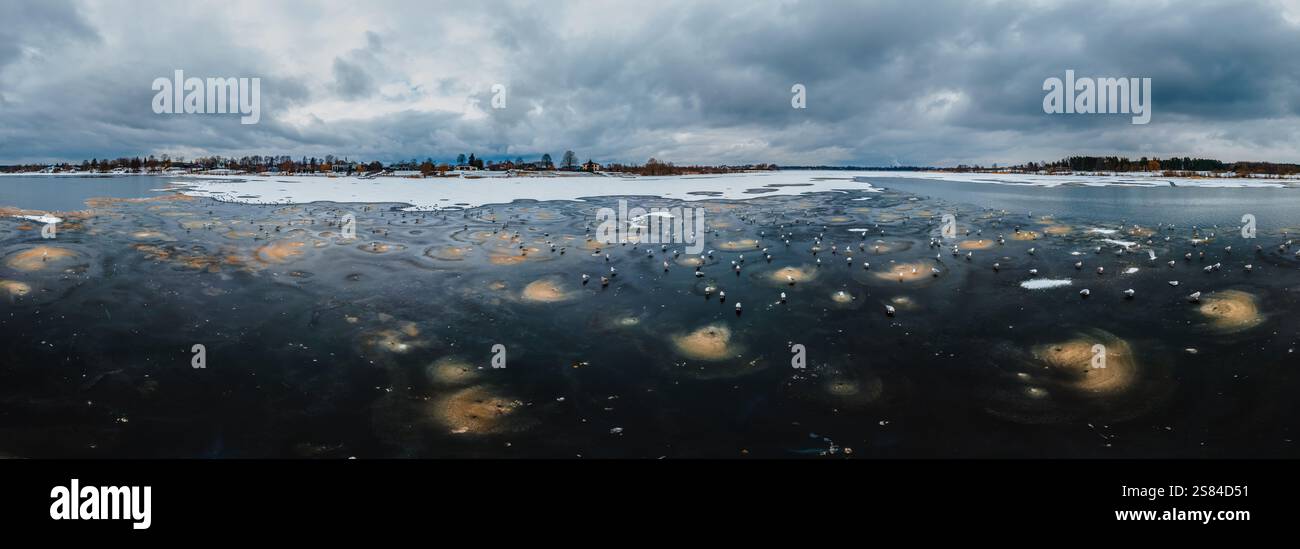 A partially frozen lake features circular ice patterns and scattered ...