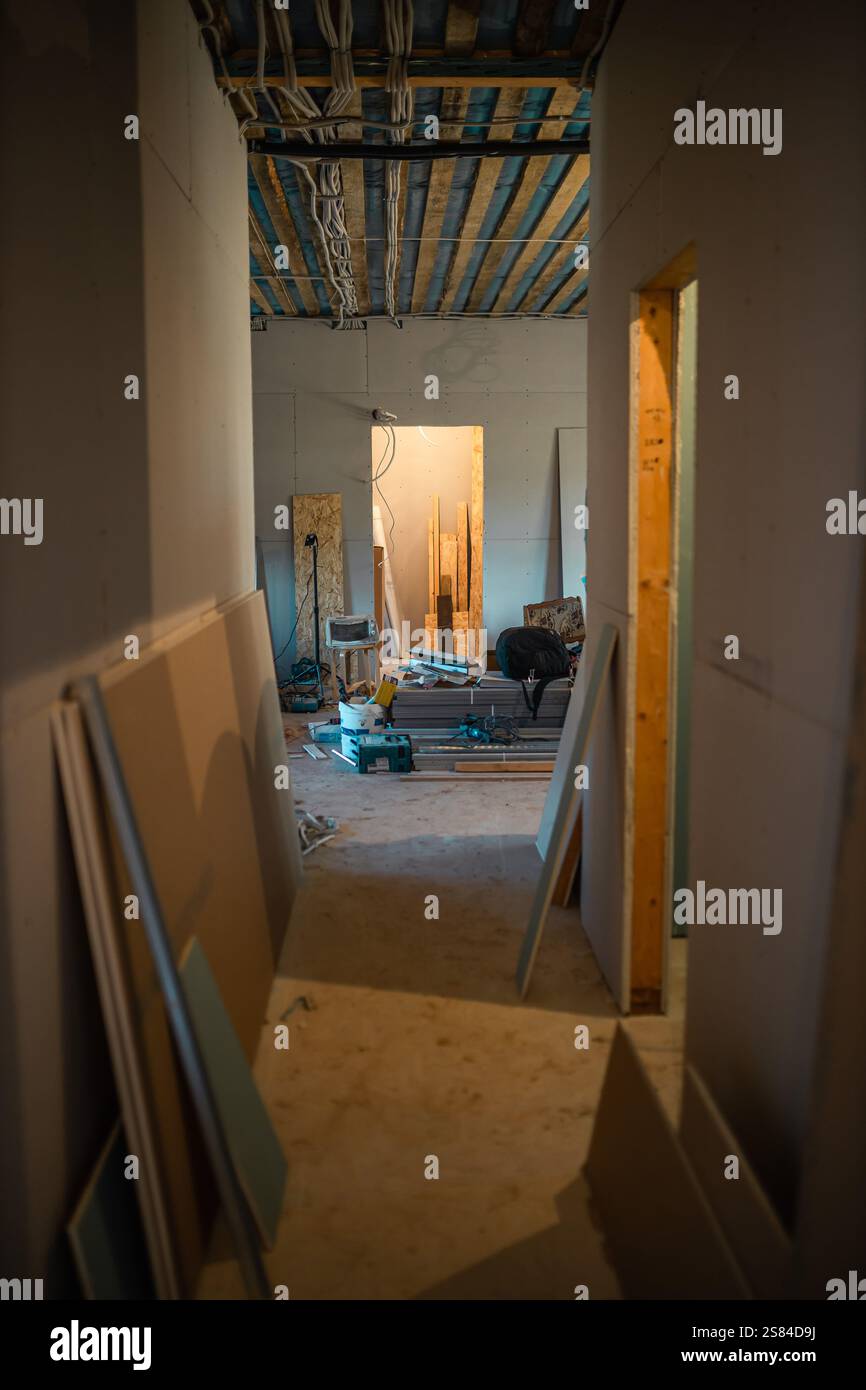 A construction site with drywall sheets, exposed wooden beams, and ...