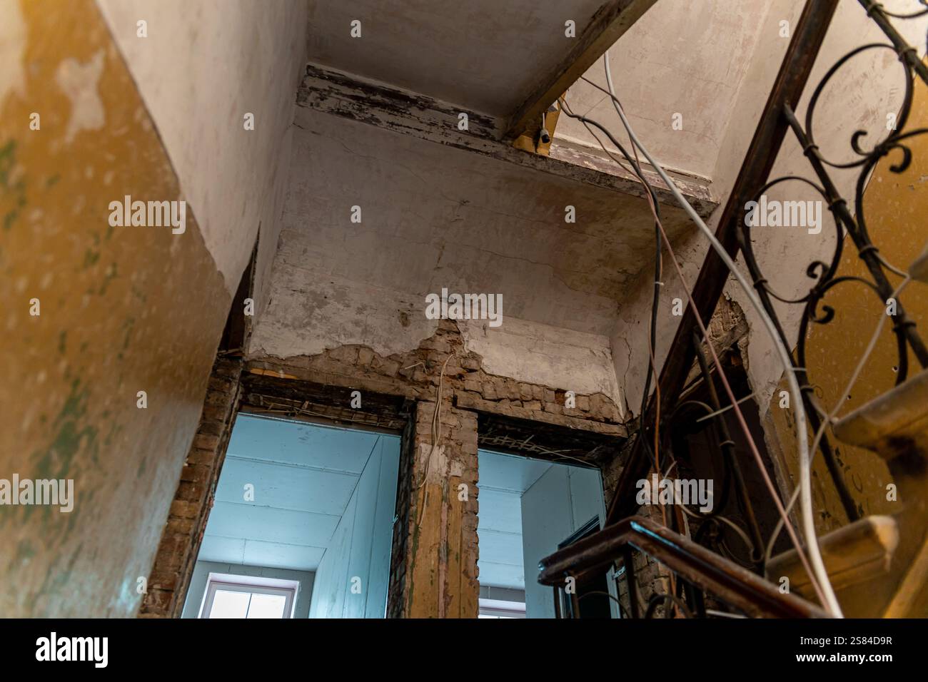 A deteriorating building interior with peeling paint, cracked plaster ...