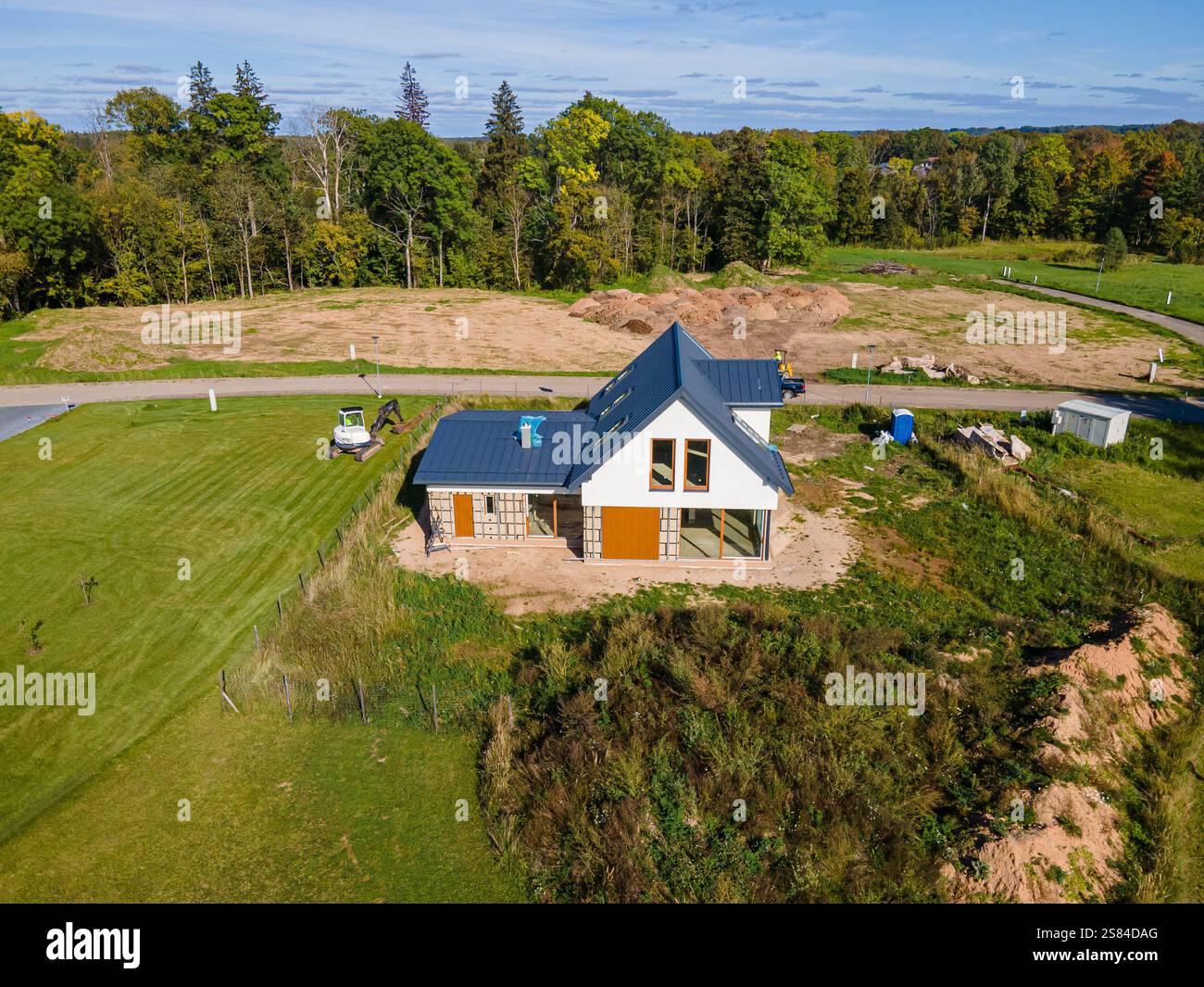 A modern house with a blue metal roof and large windows, set in a rural ...