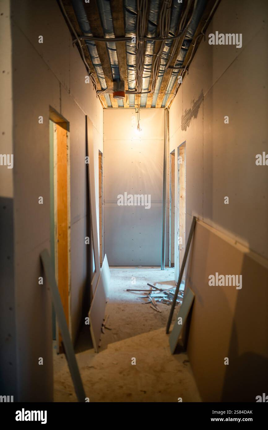 A narrow hallway under construction features unfinished drywall ...