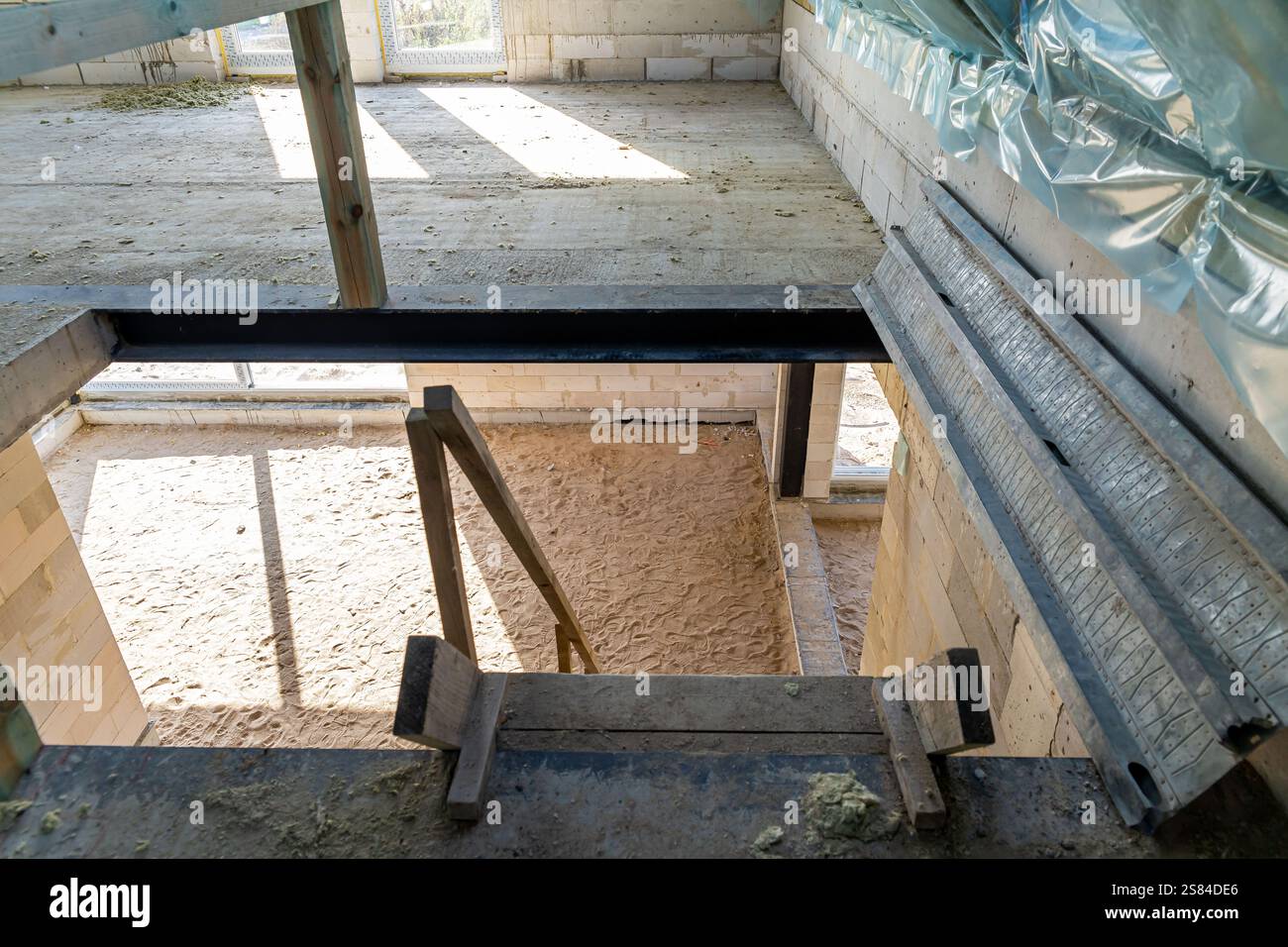 Concrete and brick walls, a wooden ladder, and sand covered floors in a ...