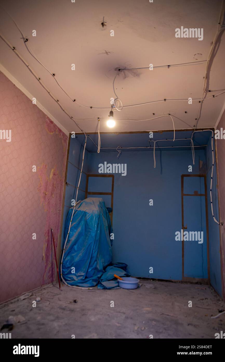 Room under renovation with exposed wiring, a single light bulb ...