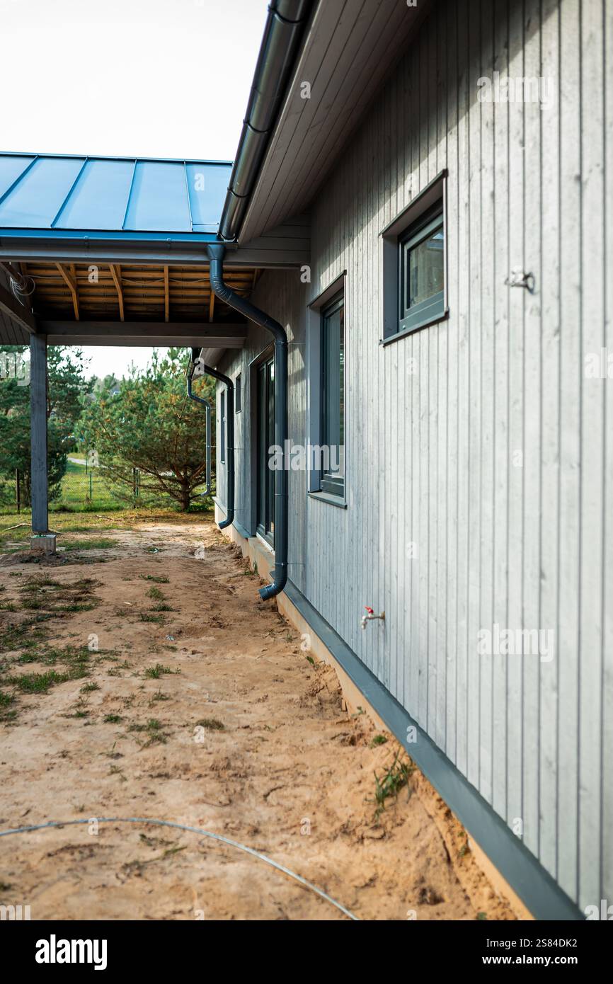Side view of a modern wooden house with light gray paneling, a blue ...