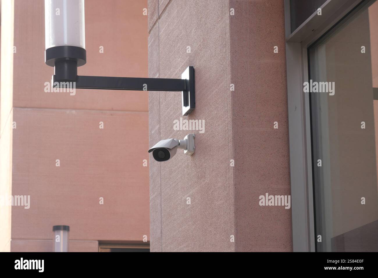 A visibly damaged security camera is mounted on a wall with its bracket ...
