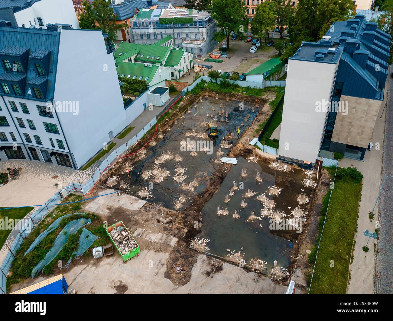 Construction site in a city with an excavator, water filled excavation ...
