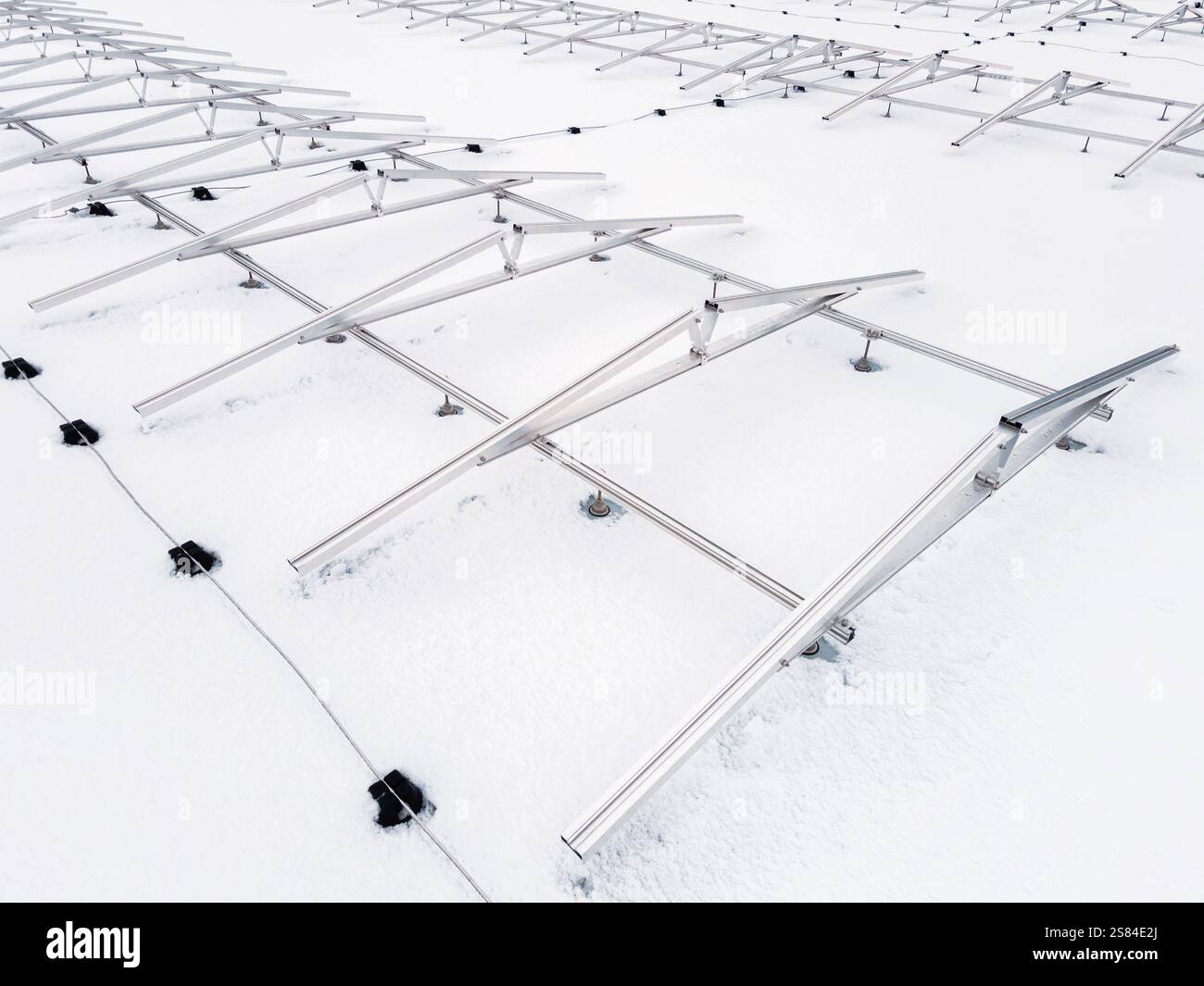 Metallic frames for solar panels stand in a grid pattern on a snow ...