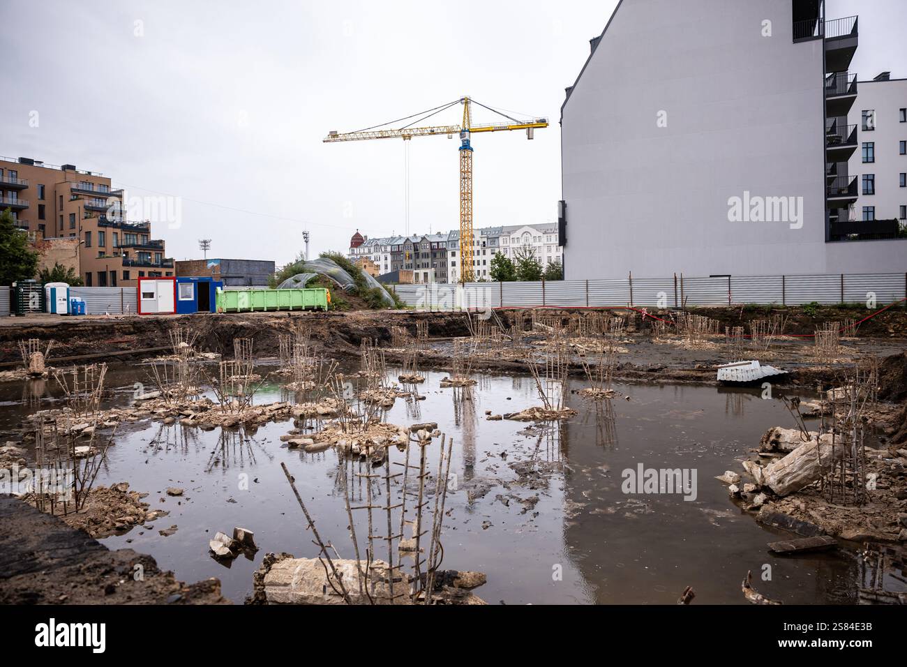 Construction site featuring a water filled excavation with rebar, a ...