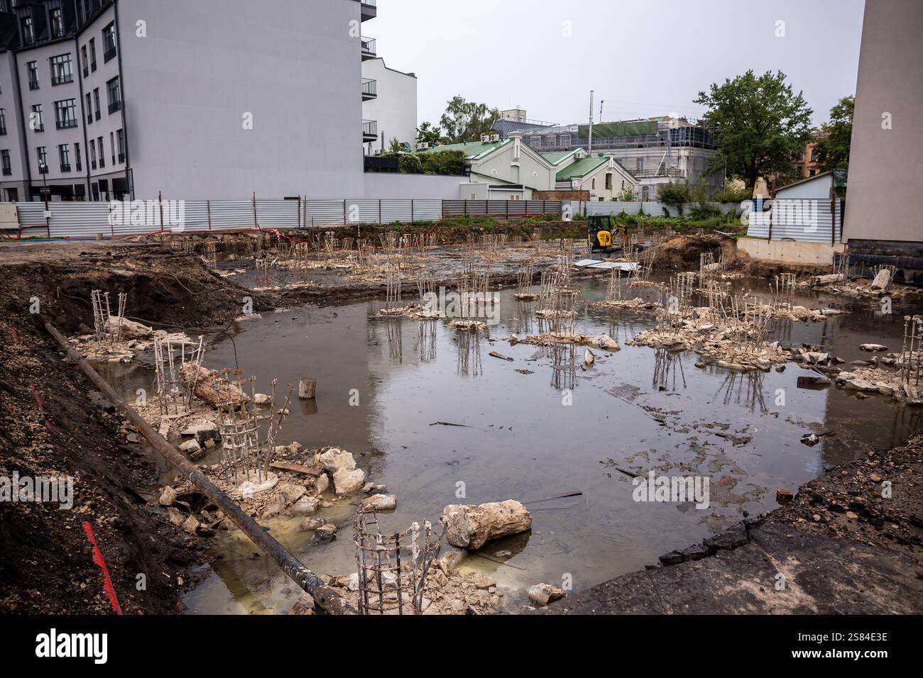Partially excavated foundation filled with water, rebar structures, and ...