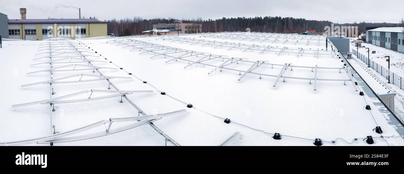 An industrial rooftop covered in snow features metal frames for solar ...