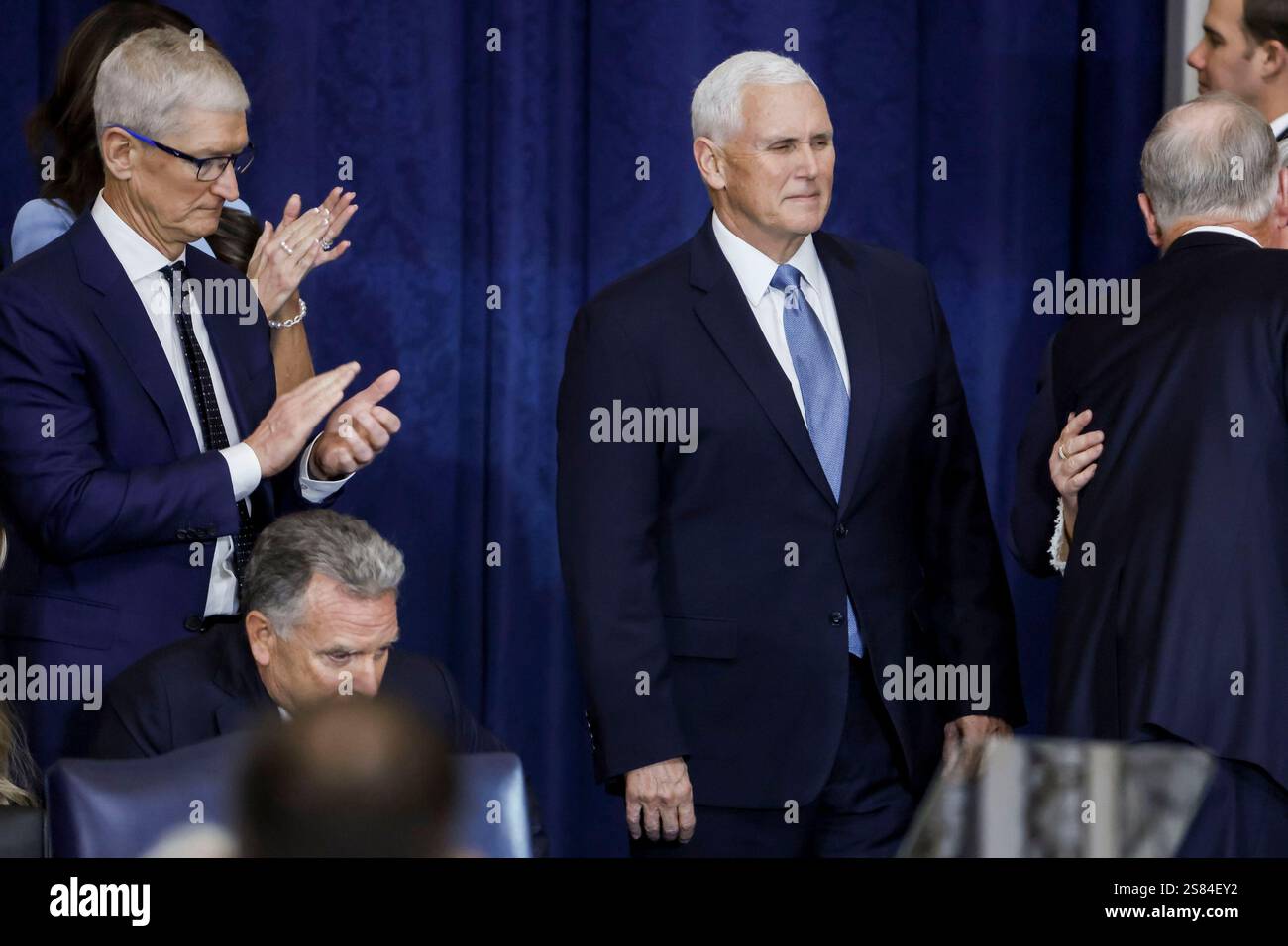 Former US Vice President Mike Pence (R) walks past Apple CEO Tim Cook ...