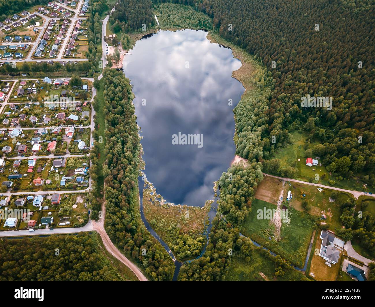 A reflective lake mirrors the sky, surrounded by forests, residential ...
