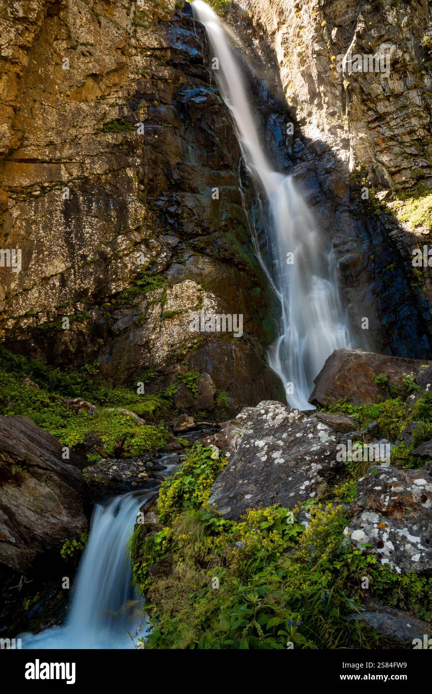 A waterfall cascades over a rocky cliff, surrounded by moss and ...
