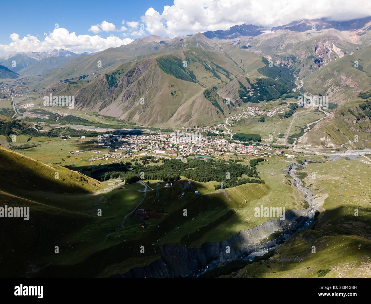 A small town lies in a valley surrounded by green and rocky mountains ...