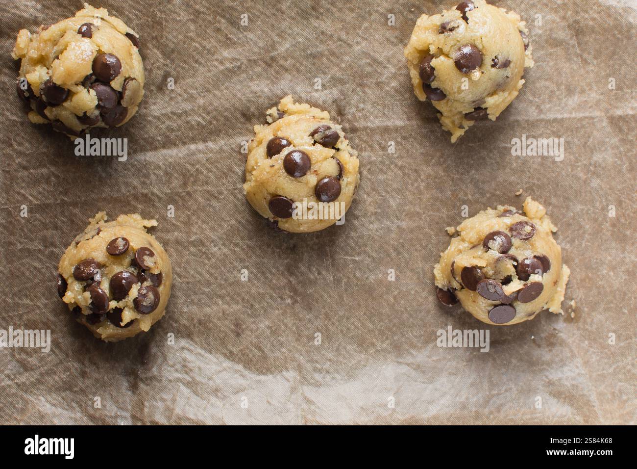 Overhead view of chocolate chip cookie dough being scooped onto a ...