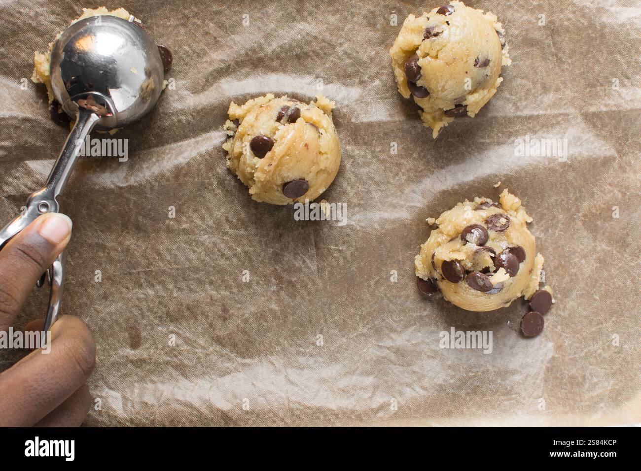 Overhead view of chocolate chip cookie dough being scooped onto a ...