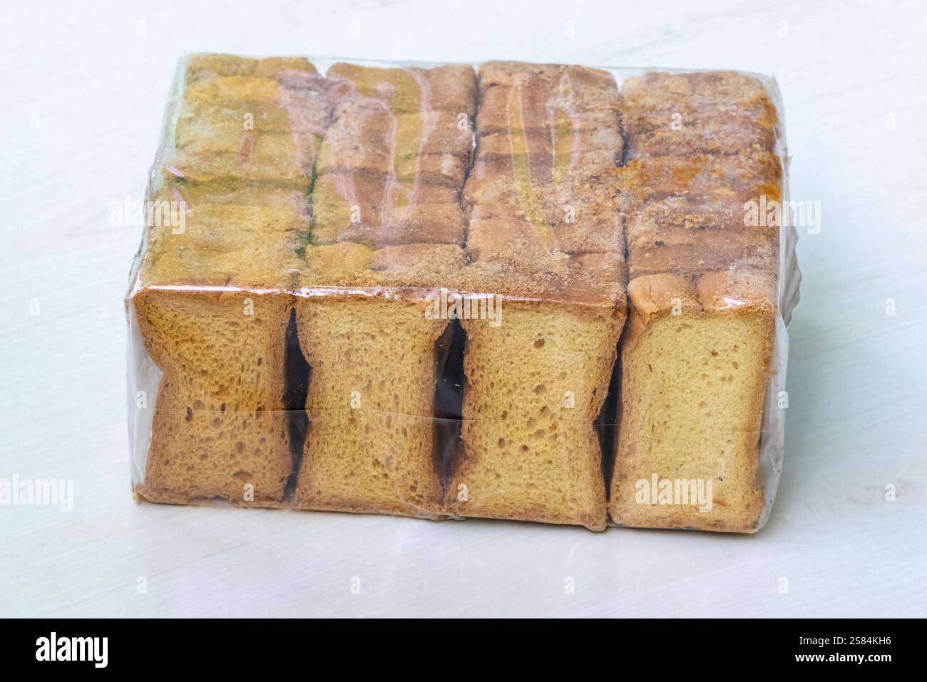 A packet of crispy rusk toast, dry cake biscuits on a light wooden ...