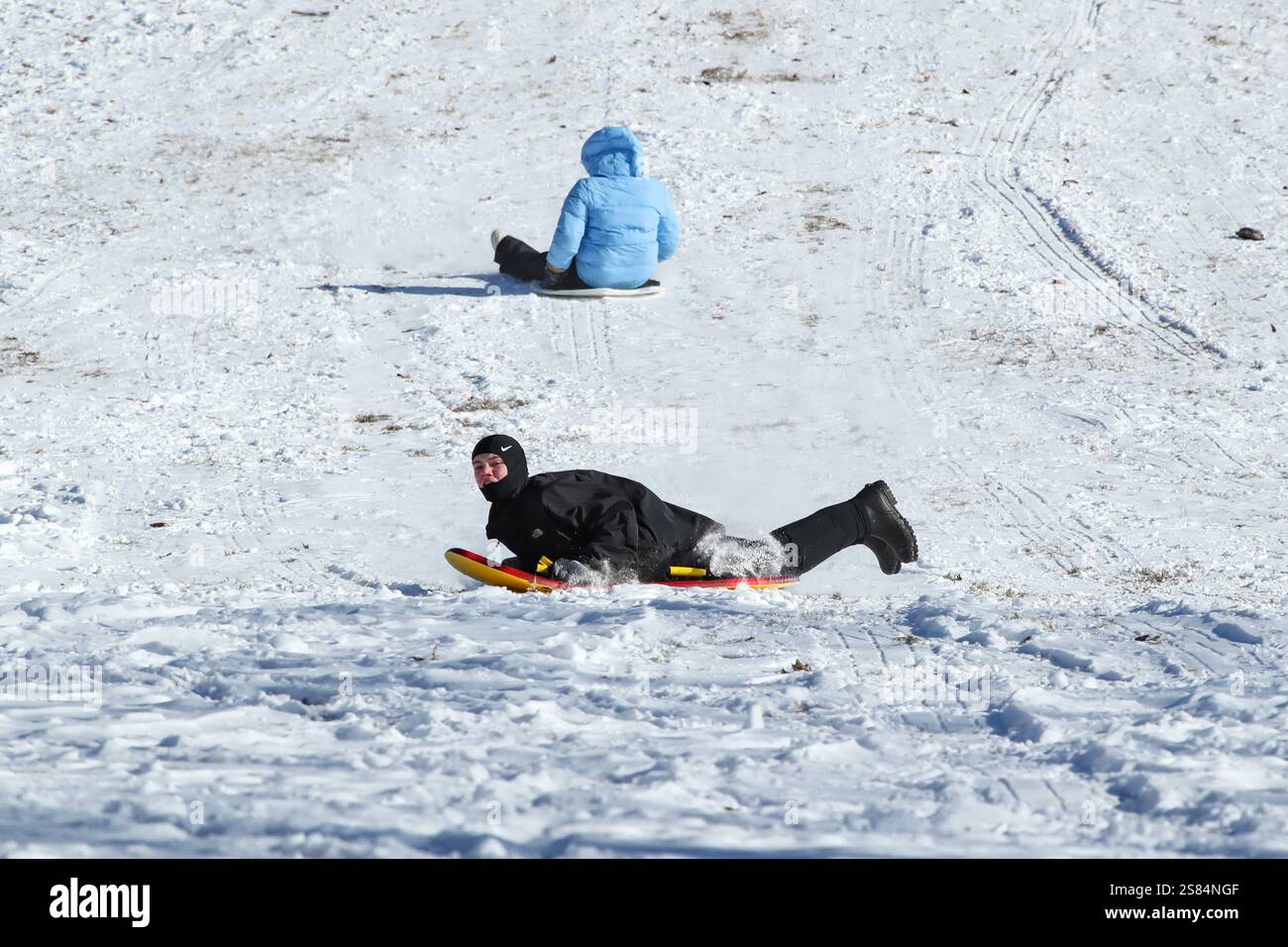 A boy sleds down a snow-covered hill. Many children used their day off ...