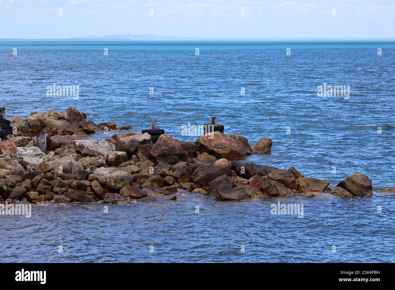 rocky makeshift boat mooring cove with tire bumpers juts into blue ...