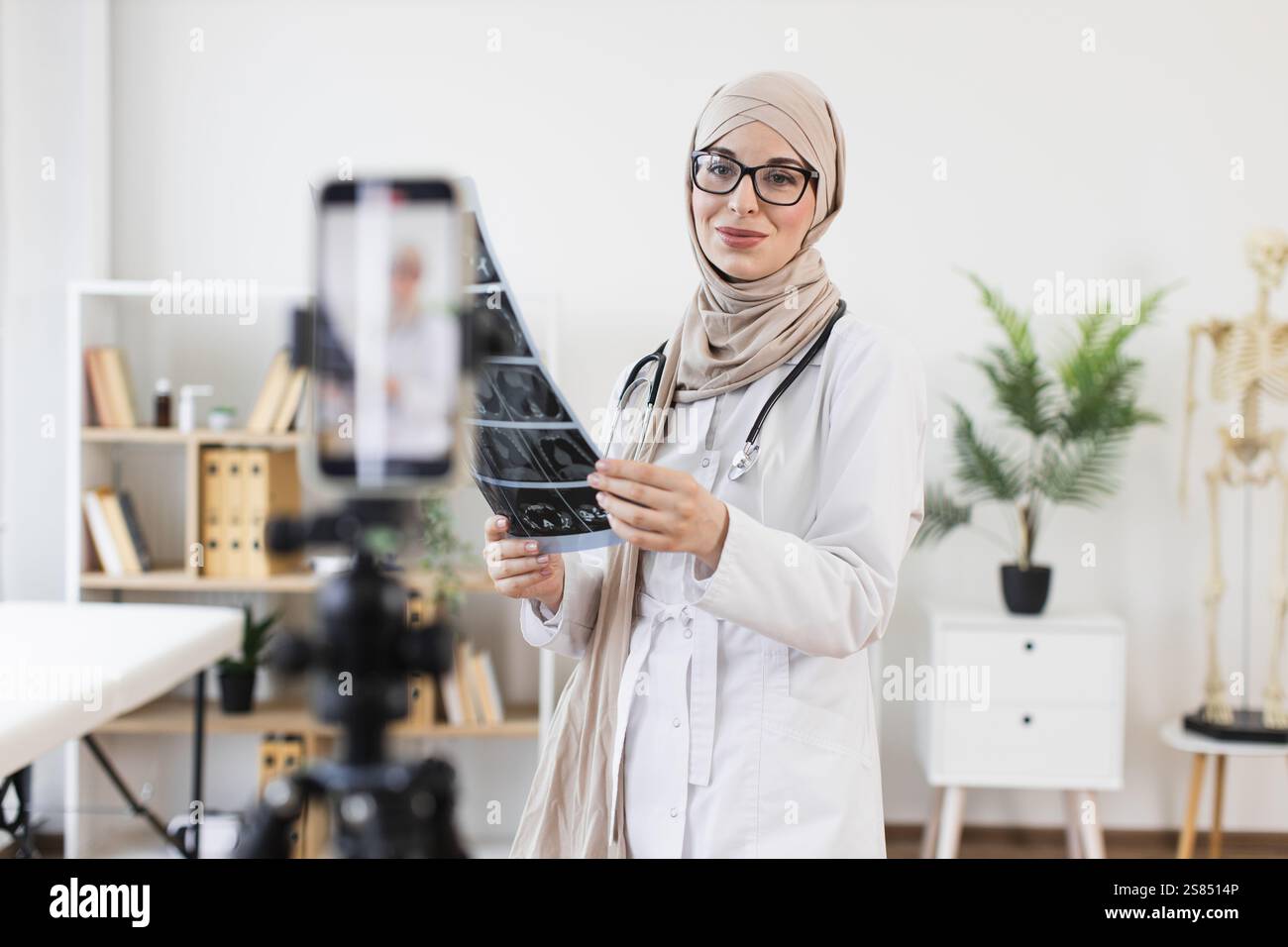 Muslim woman doctor recording educational video with x-ray ...