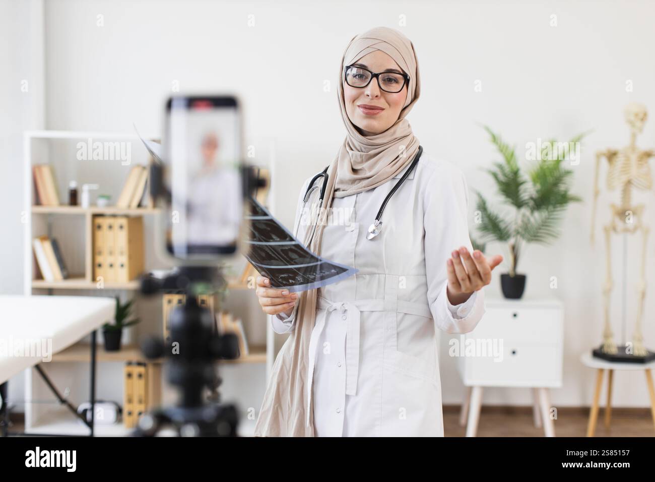 Muslim woman doctor recording educational video with x-ray ...