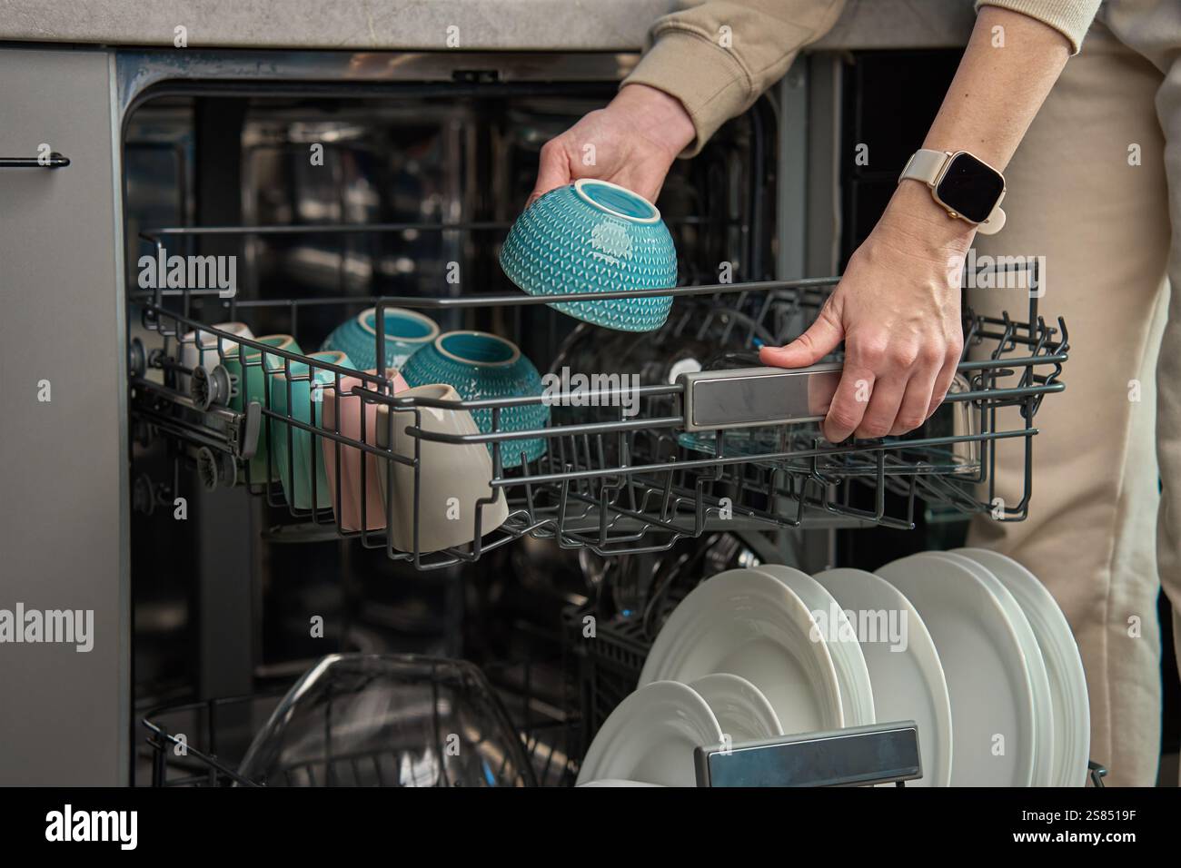 Woman unloading clean dishes and colorful bowl from dishwasher in ...