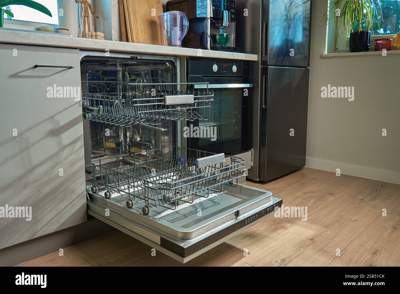 Open empty dishwasher with empty racks and extended basket in modern ...