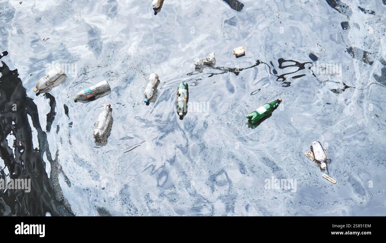 Plastic bottles and other garbage floating on polluted water surface ...