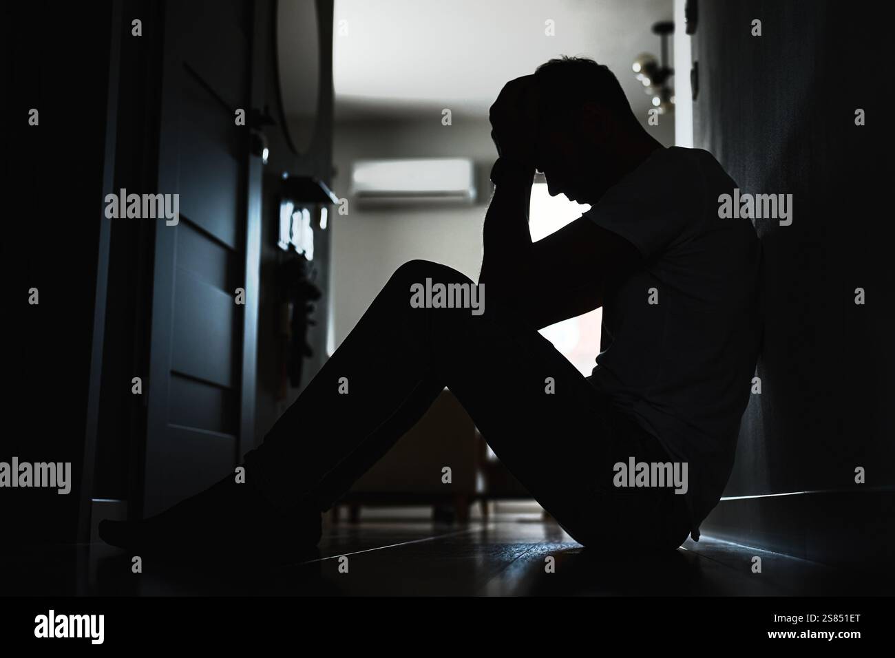 Depressed young man sitting on floor in dark room. Silhouette of young ...