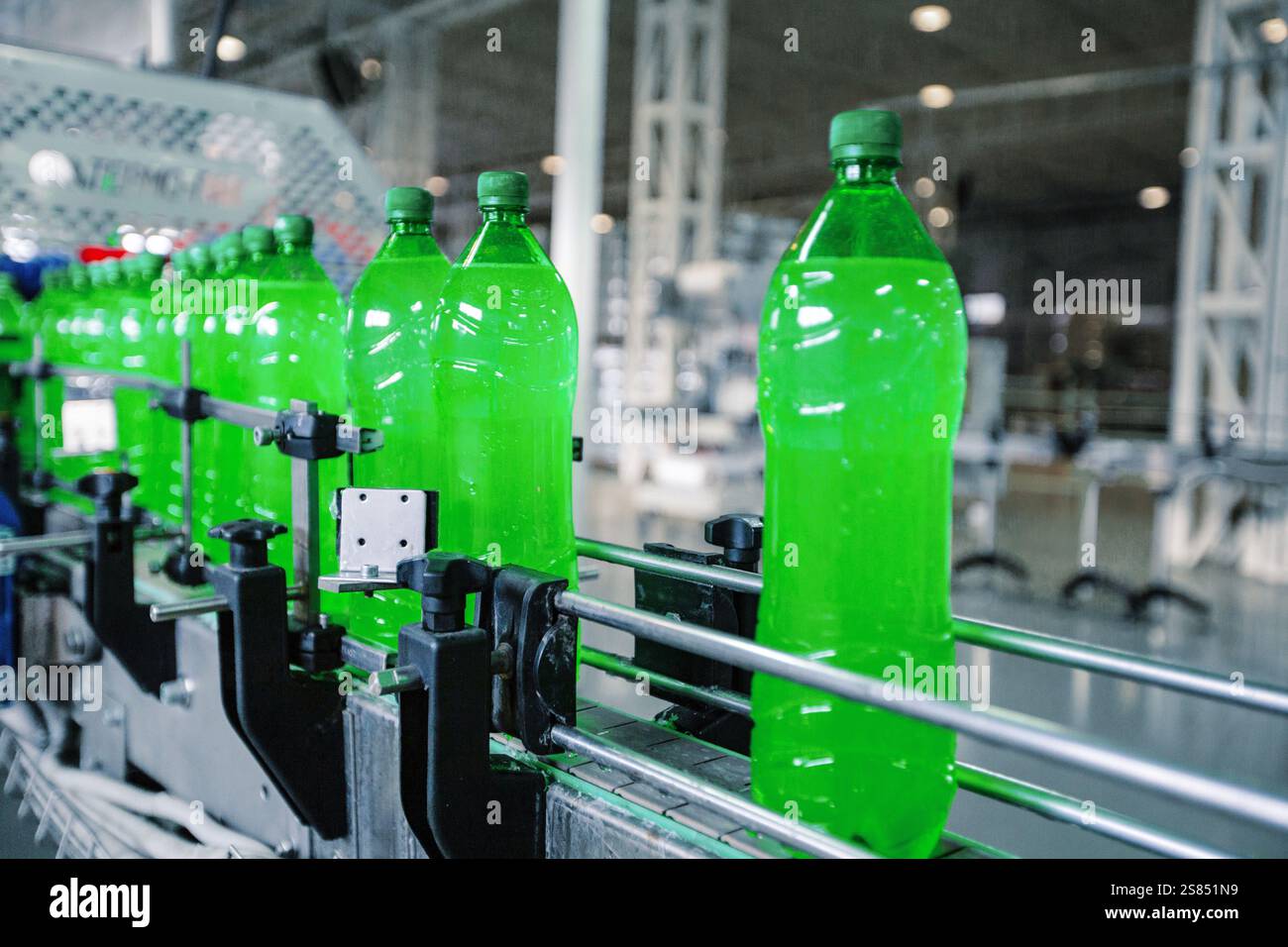 Bottles of green soda moving along a production line in a beverage ...