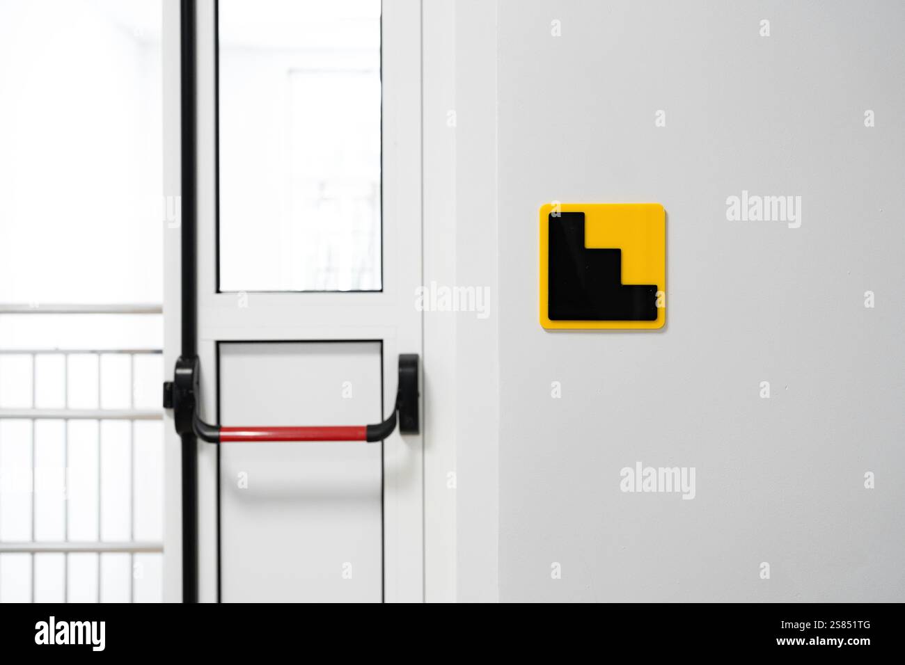 Door with a handle and a directional sign indicating stairs in a modern ...