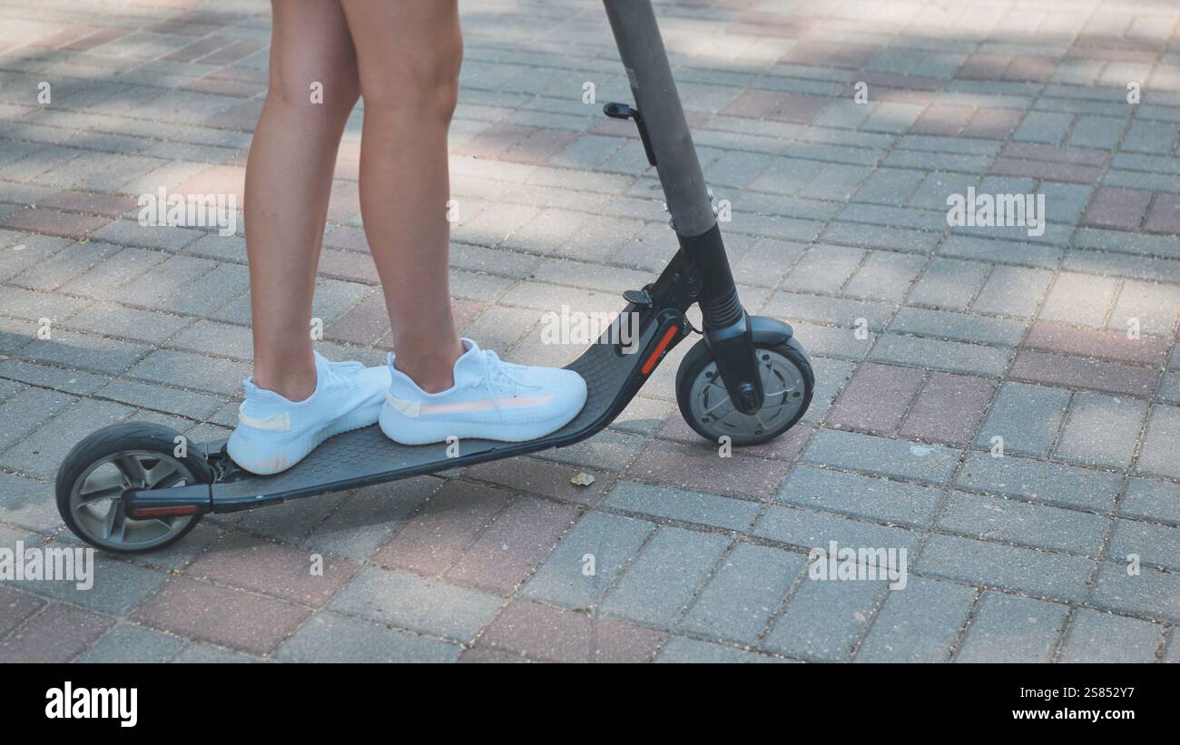 Teenage girl riding electric scooter, legs close up, summer park ...