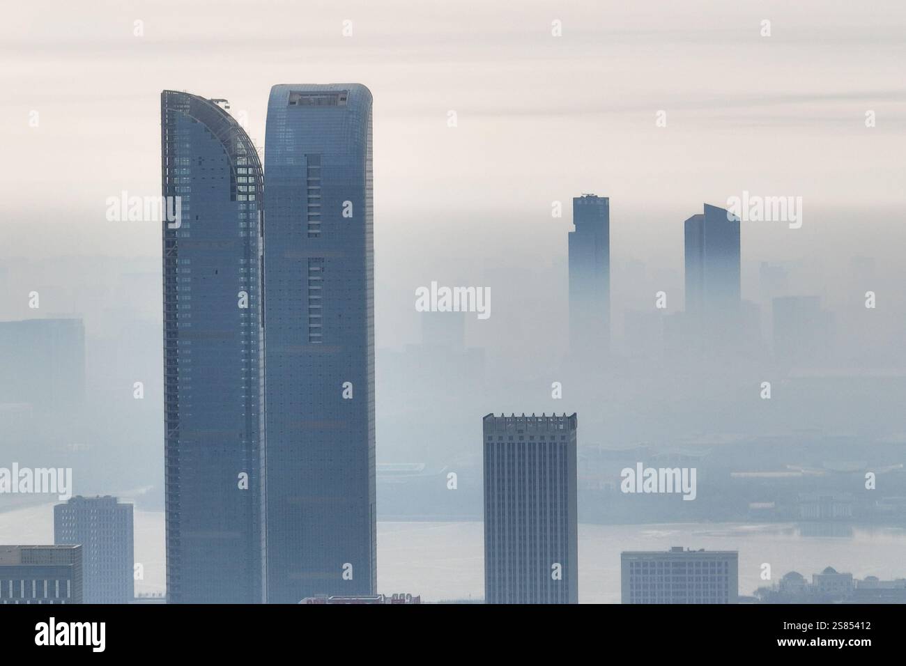 A cluster of urban buildings looms in the morning fog in Yinchuan city ...