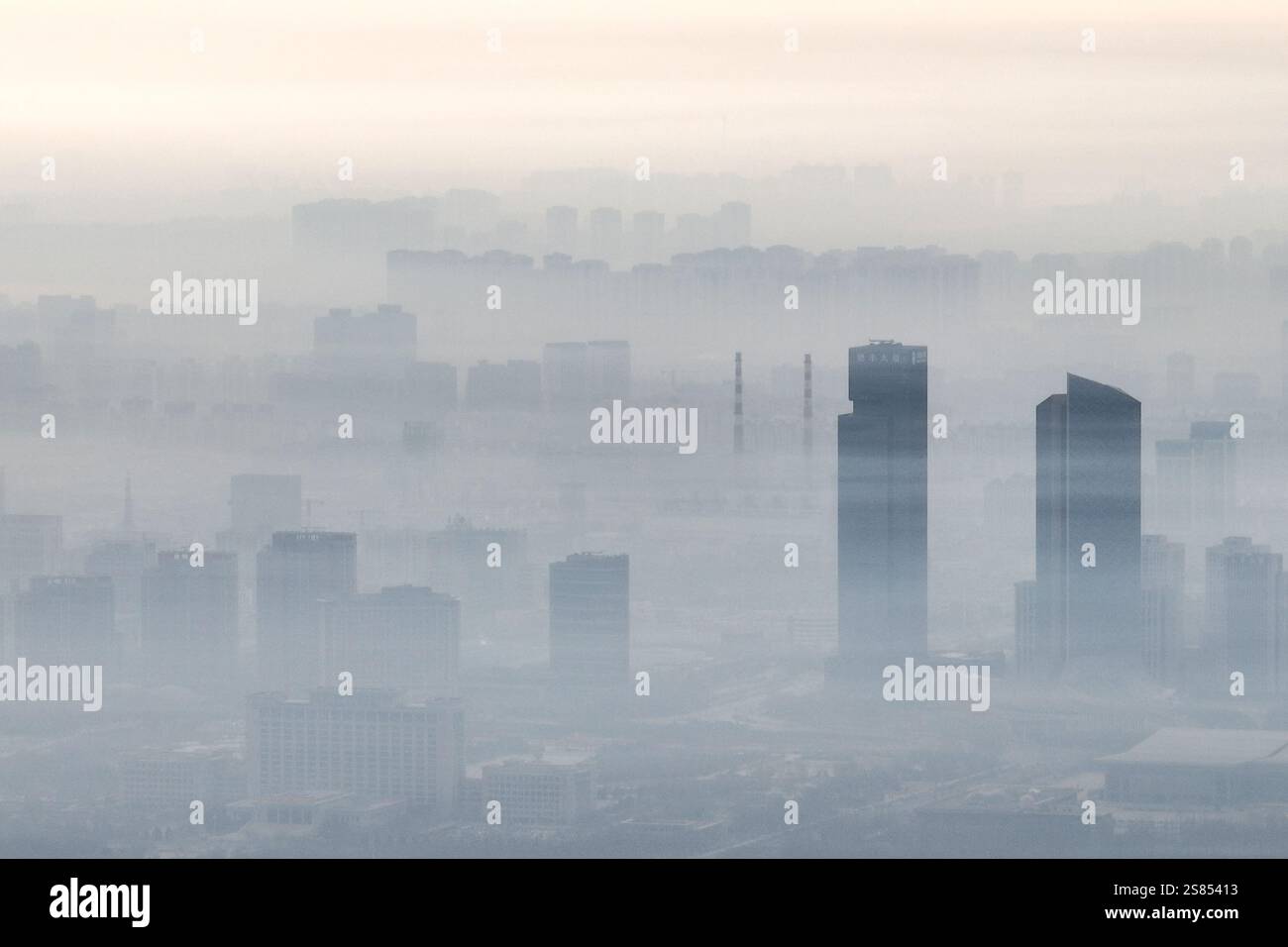 A cluster of urban buildings looms in the morning fog in Yinchuan city ...