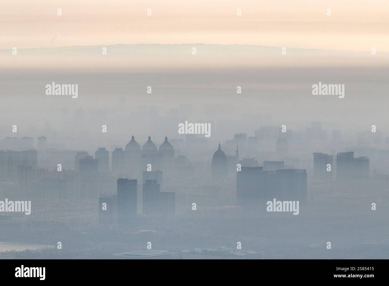 A cluster of urban buildings looms in the morning fog in Yinchuan city ...
