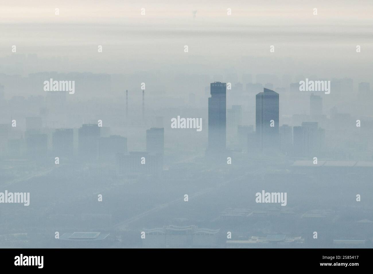 A cluster of urban buildings looms in the morning fog in Yinchuan city ...