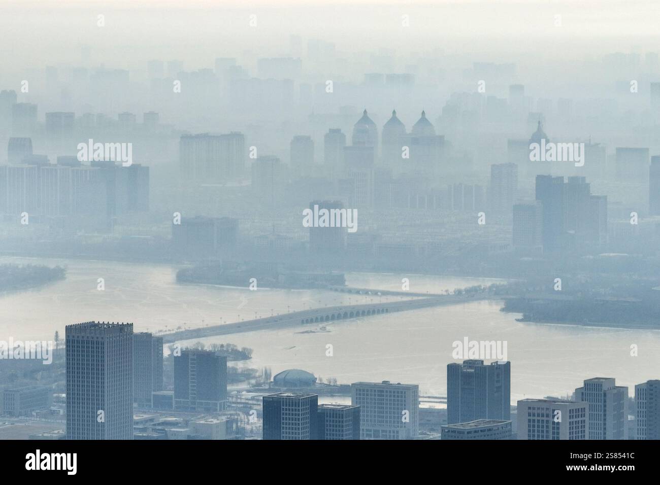 A cluster of urban buildings looms in the morning fog in Yinchuan city ...